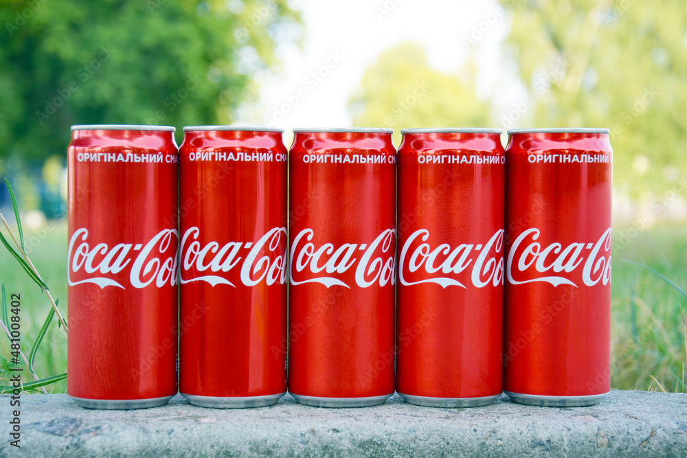 Many cans of Coca-Cola soda with background blurring in a park. Stock ...