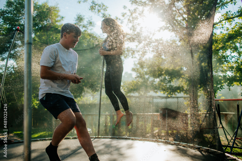Two teenagers jumping on trampoline outside Stock Photo | Adobe Stock