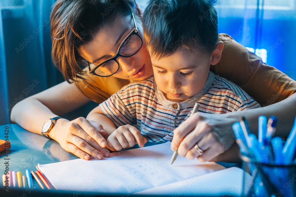 Little boy doing homework at home with school books helped by his ...