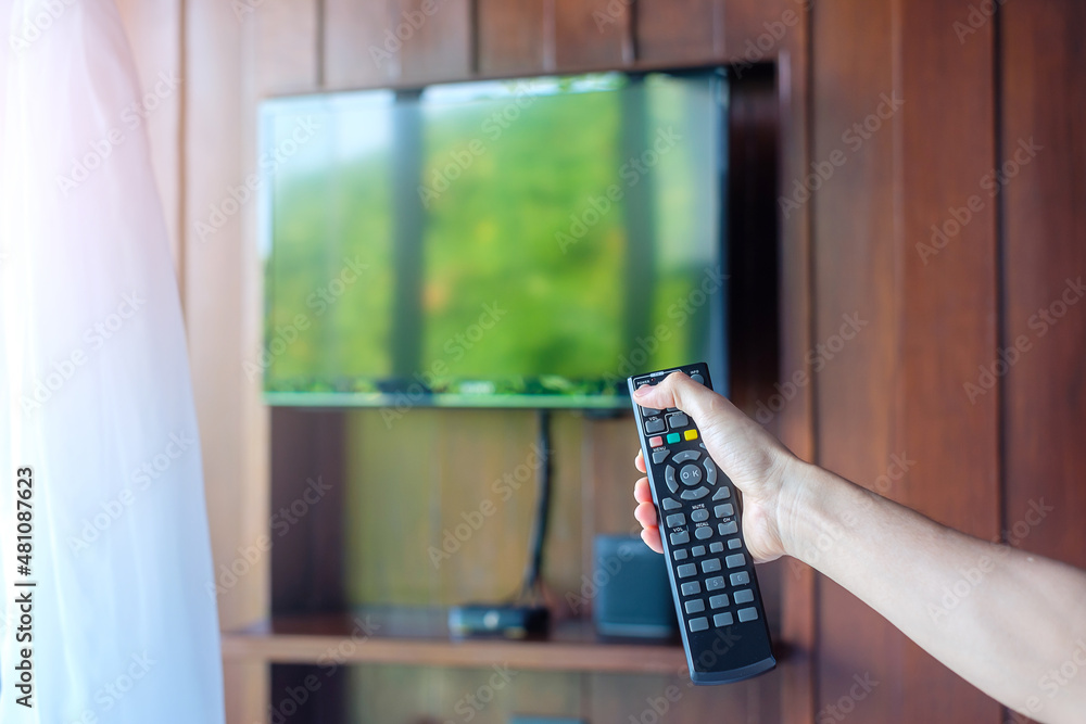 hand using remote controller for adjust Smart TV inside the modern room ...