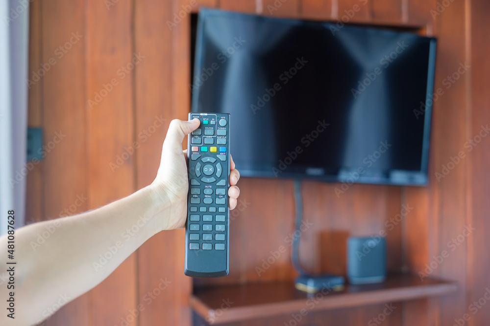hand using remote controller for adjust Smart TV inside the modern room ...