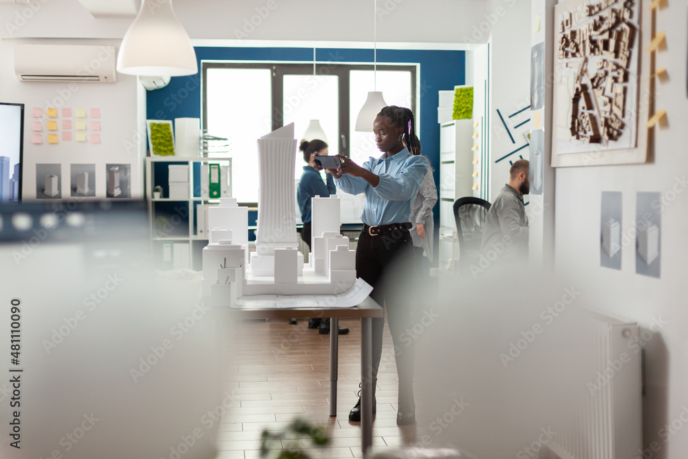 Architect working with smartphone to photograph maquette of skyscraper ...