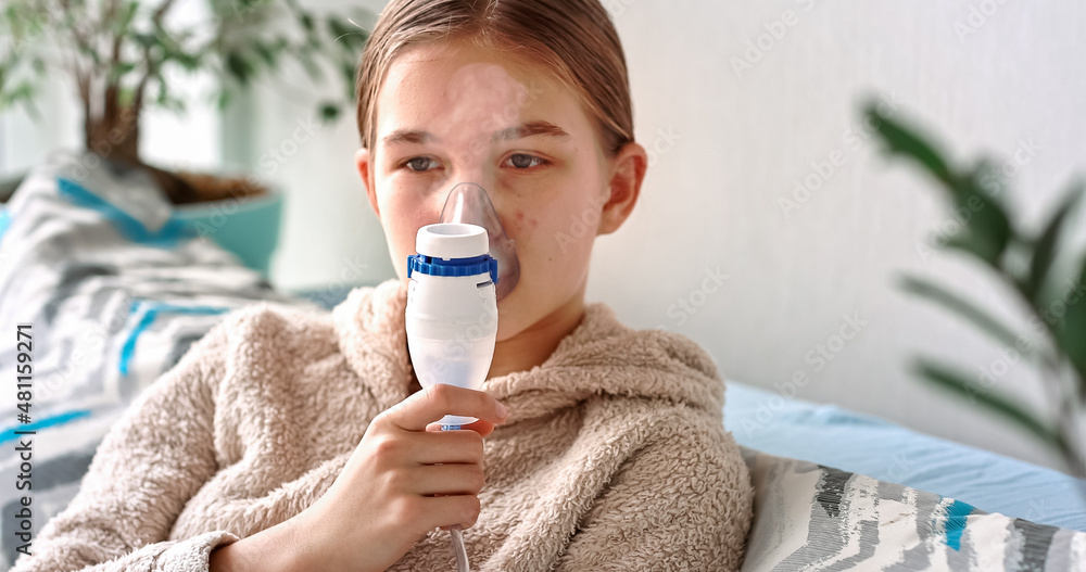 Teenage girl makes inhalation with a nebulizer equipment. Sick child ...