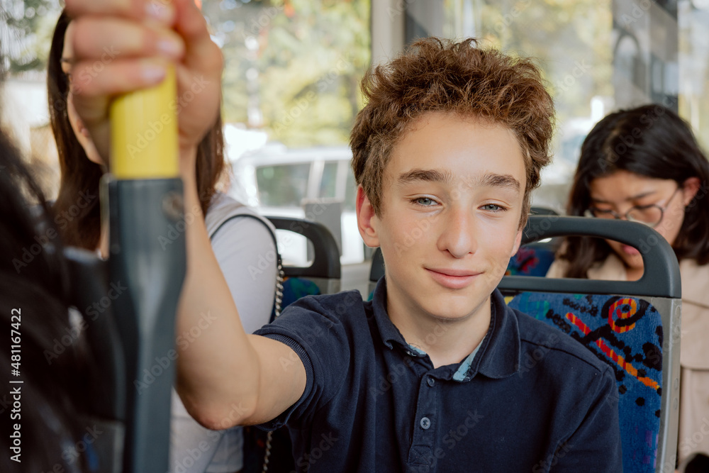 Young boy with curly light hair sits on public transport bus, holds on ...