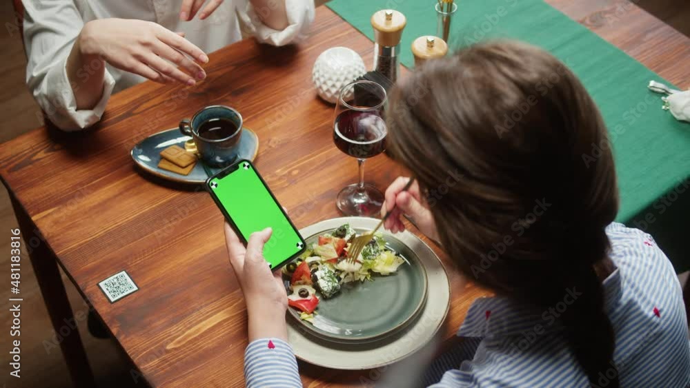 Woman using smartphone with chroma green screen and eating salad. QR ...