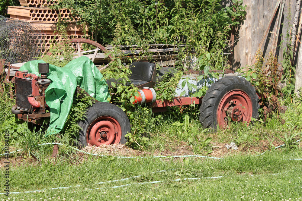 The abandoned wreck of a homemade tractor standing in the garden ...