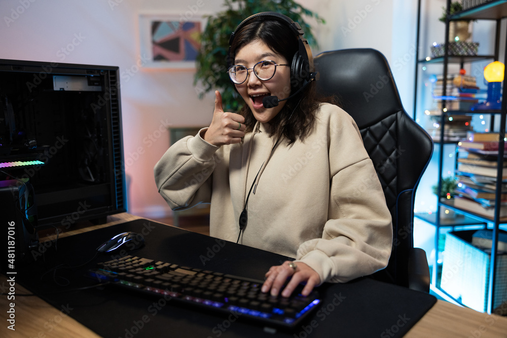 Happy smiling gamer girl shows thumbs up, won a round in a computer ...