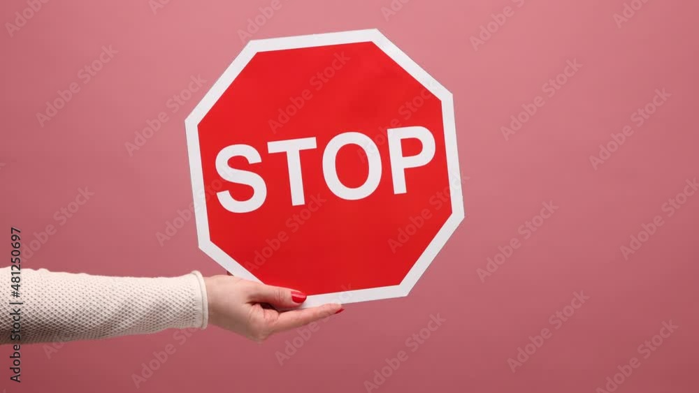 Profile side view of woman hand holding octagonal red stop symbol, ban ...
