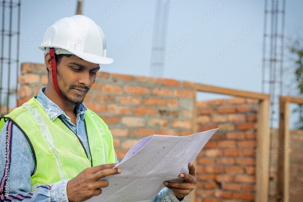 Engineer at construction site reading blueprint drawing. Stock Photo ...