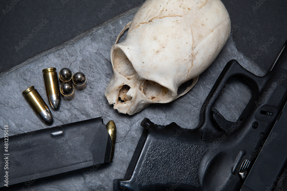 Skull and pistol with bullets against a black stone background (monkey ...