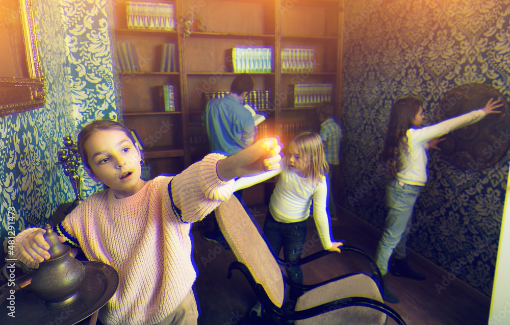 Tween girl trying to reach out some item in escape room, holding out ...