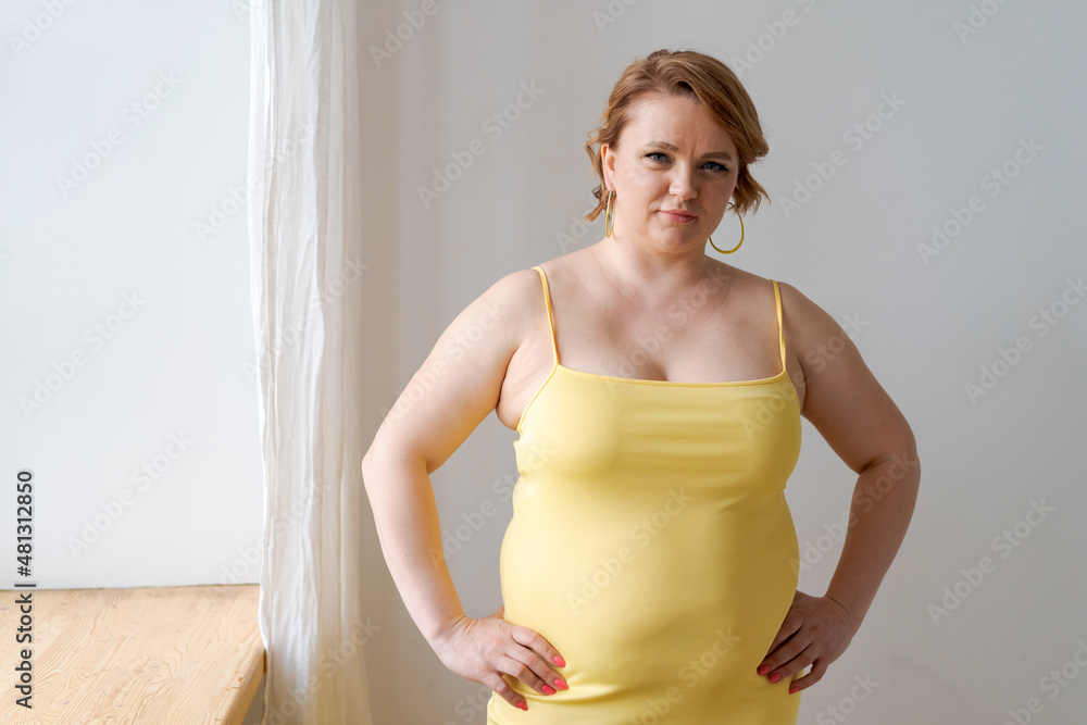 Portrait cheerful attractive young plump plus size woman in yellow ...