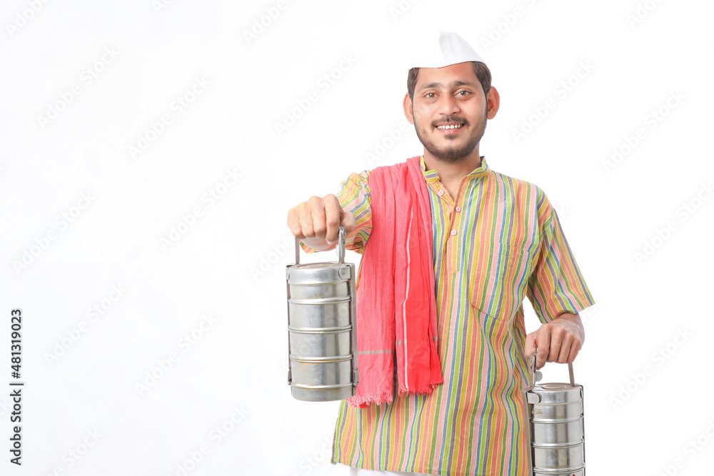 Young indian common man in traditional wear holding tiffin box in hand ...
