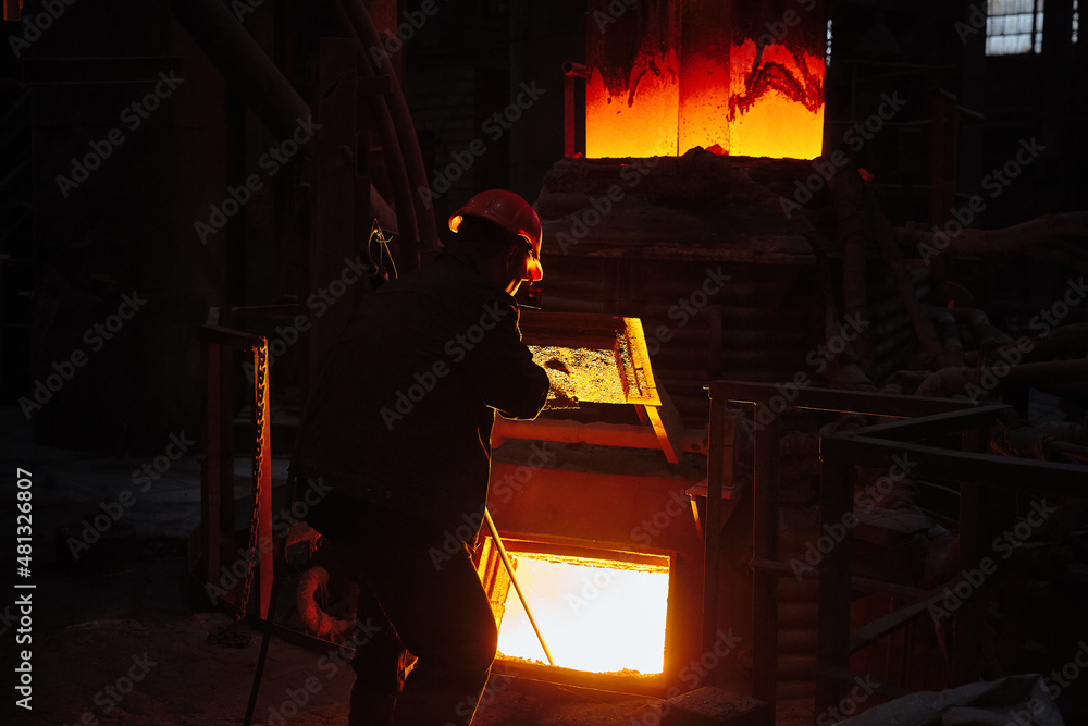 Metallurgist steelmaker takes a sample of liquid metal from a ladle ...