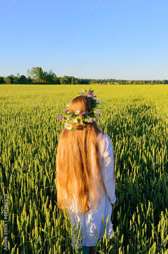 Long haired girl dreesed in white with the frower wreath on the head ...