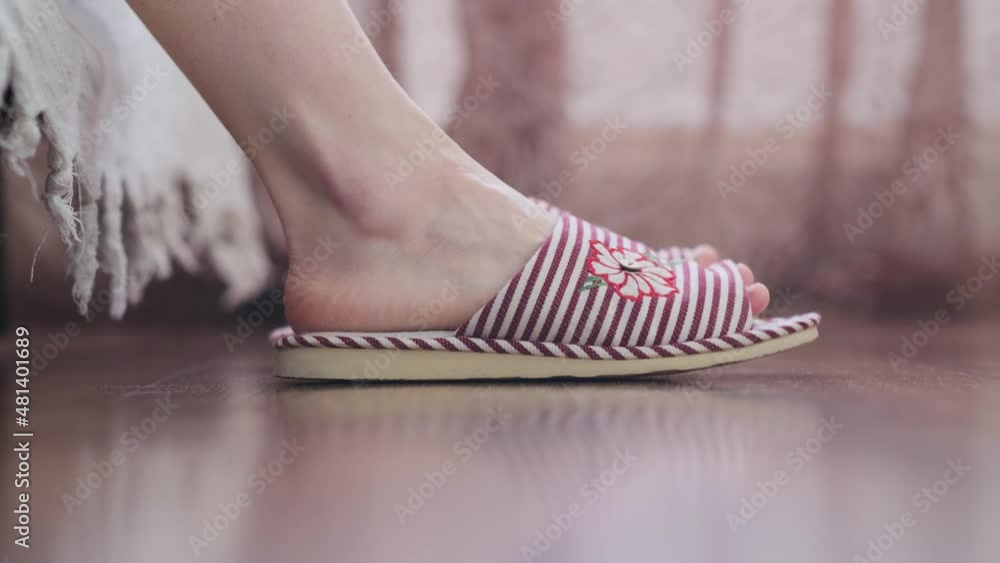 4k, woman's feet put on slippers, on the wooden floor. Side view ...