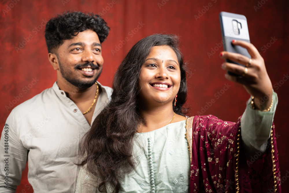Beautiful Indian couple taking selfie using smartphone on studio ...