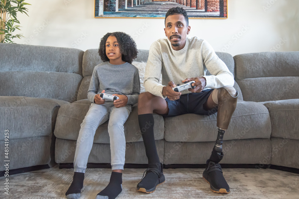 Boy playing video game with father with prosthetic leg Stock Photo ...