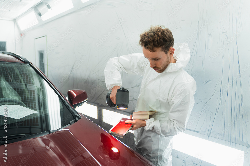 Car painter man determines the correct tone of a vehicle body colour ...