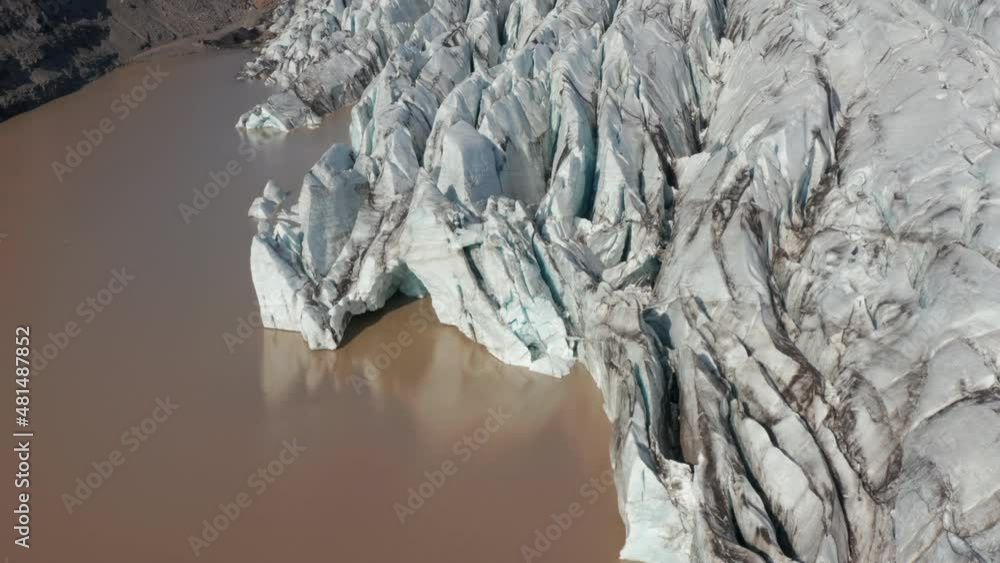 High angle view of water surface and end of glacier. Tilt up reveal of ...