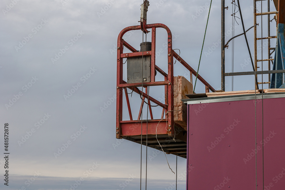 Suspended construction cradle on the background facade of the building ...