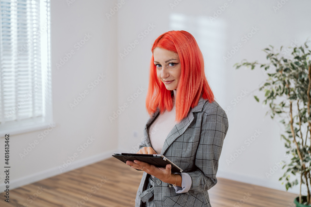 Smiling elegantly dressed woman stands in middle of an empty room in ...