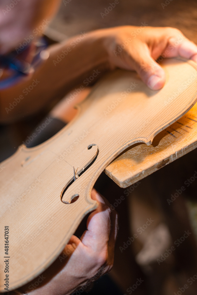 Luthier making a handmade classic italian violin, working and carving ...