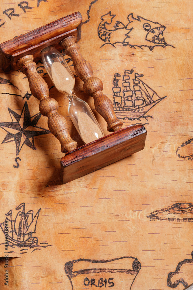 An hourglass lying on the order of antique nautical chart depicting ...