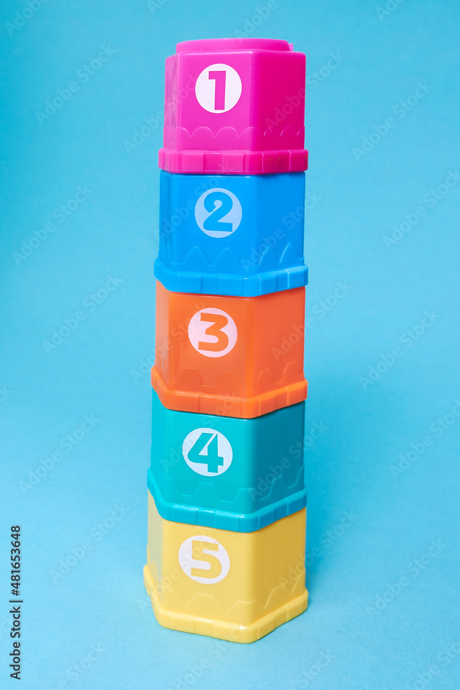 Children's multi-colored plastic toy pyramid on a blue background lies ...