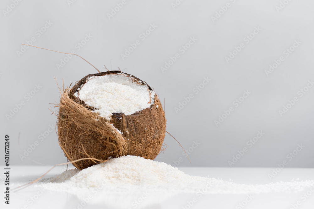 Coco abierto lleno de coco rallado que se derrama sobre una mesa blanca ...