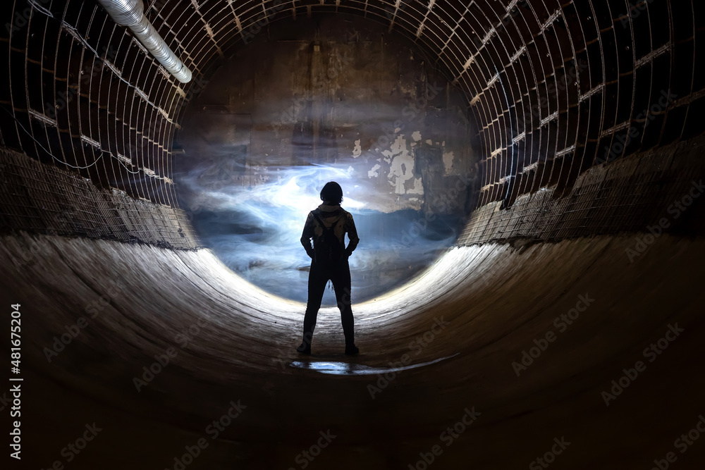Silhouette of a man in a long underground tunnel in a bunker. Light and ...