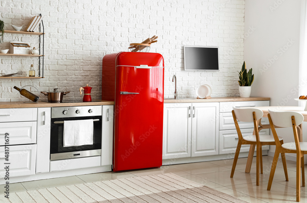 Interior of light kitchen with red fridge, white counters and dining ...