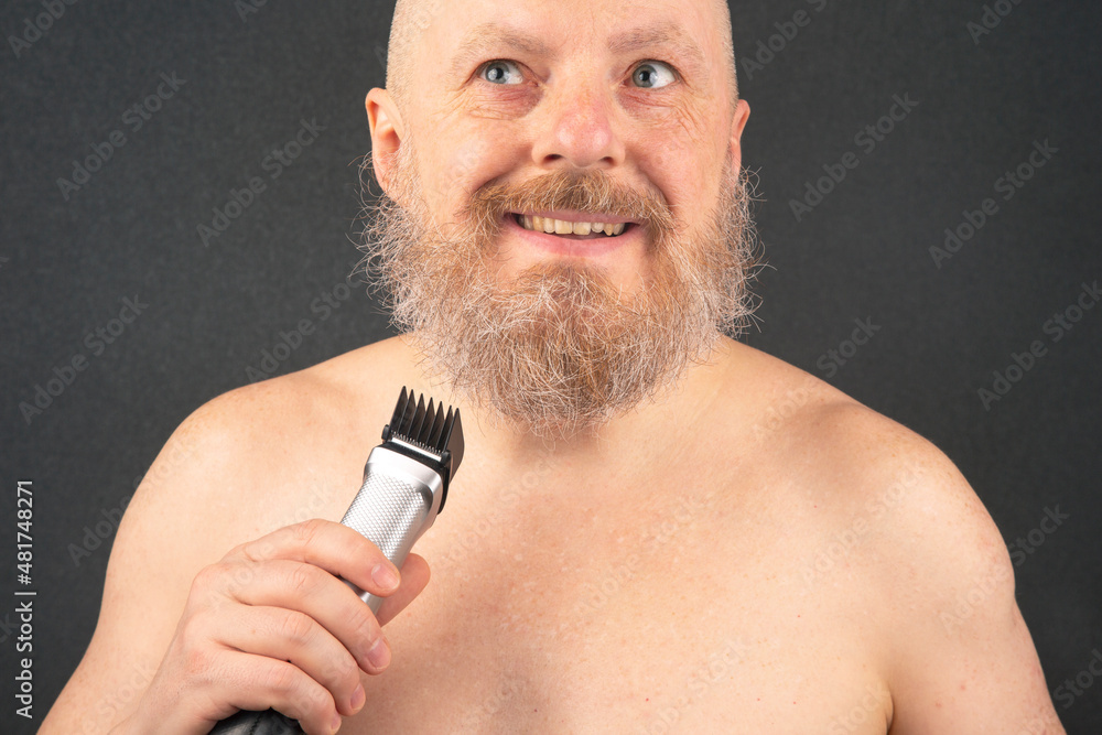 Bearded man with trimmer to adjust beard in hand. grooming and ...