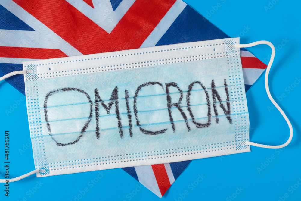 The flag of the United Kingdom and a medical mask with Omicron written ...
