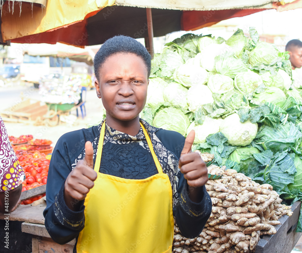 Happy African business woman or female trader wearing a yellow apron ...