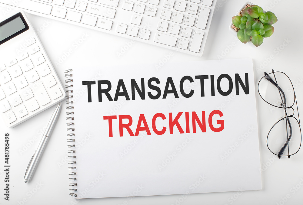 Office desk table with keyboard, notepad and calculator. Top view with text TRANSACTION TRACKING ...