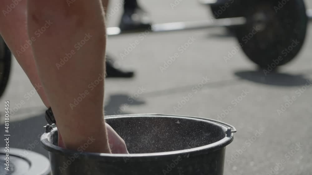 Close-up of young man puts chalk on his hands from bucket and claps so ...