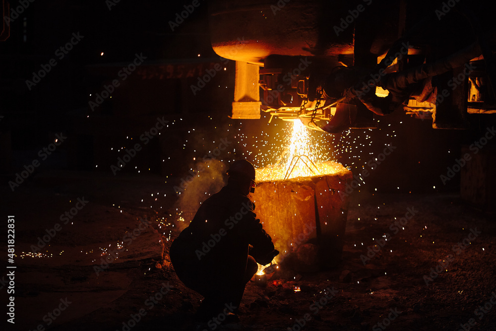 Metallurgist steelmaker takes a sample of liquid metal from a ladle ...
