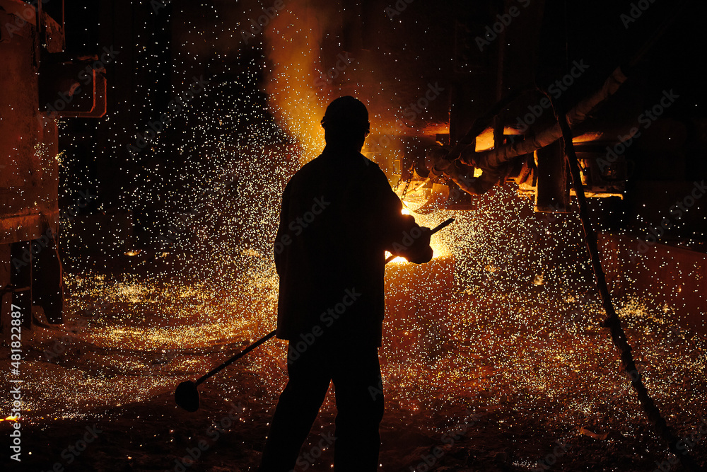 Metallurgist steelmaker takes a sample of liquid metal from a ladle ...