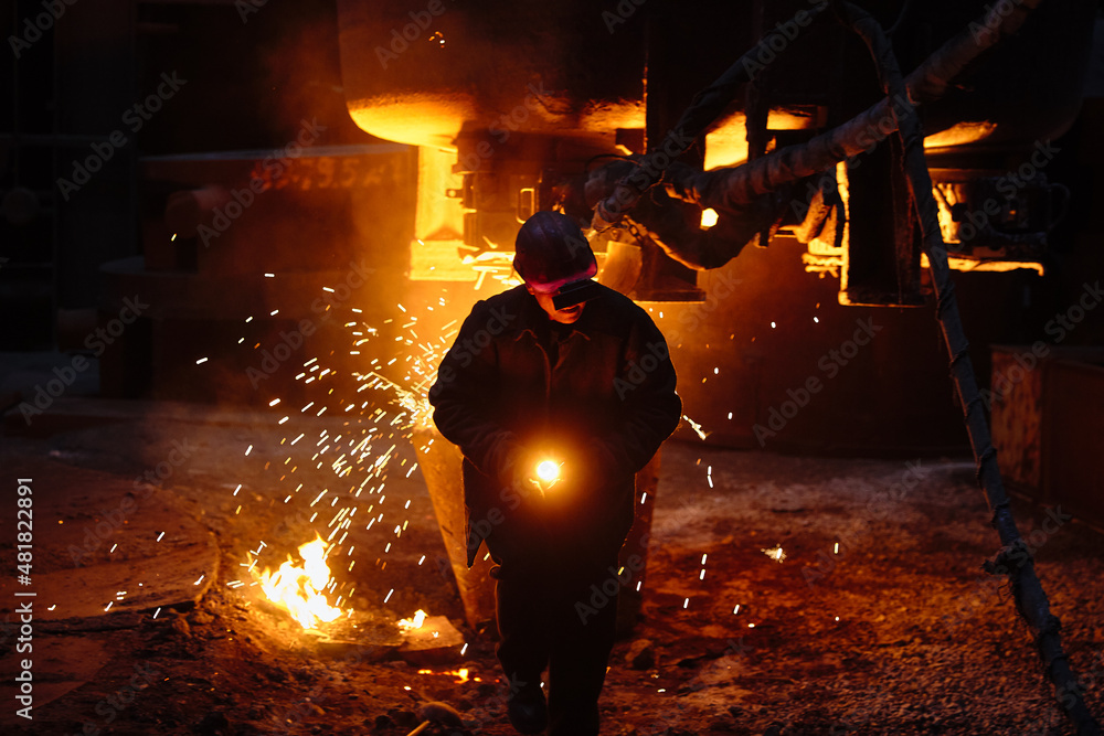 Metallurgist steelmaker takes a sample of liquid metal from a ladle ...