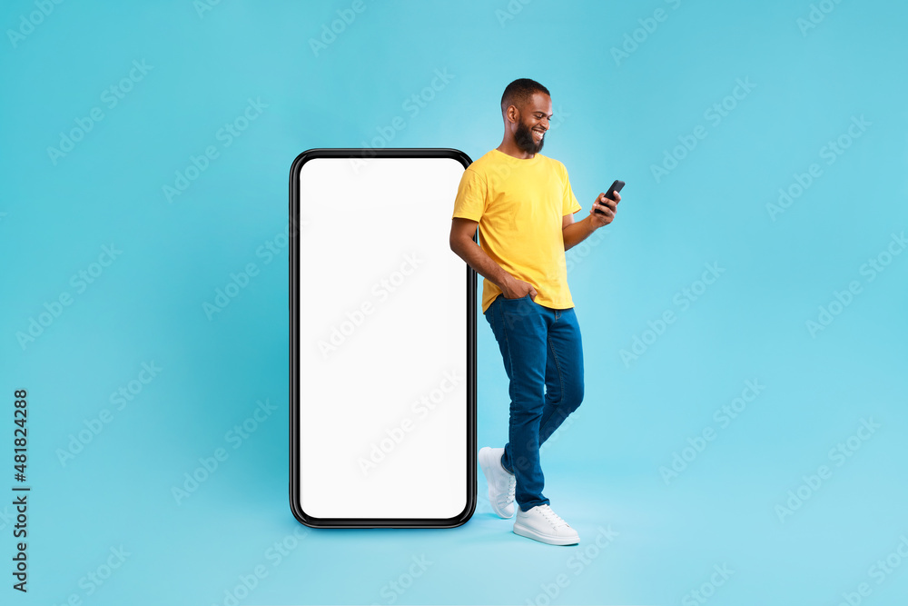 Handsome young Afro man using mobile phone while standing near huge ...