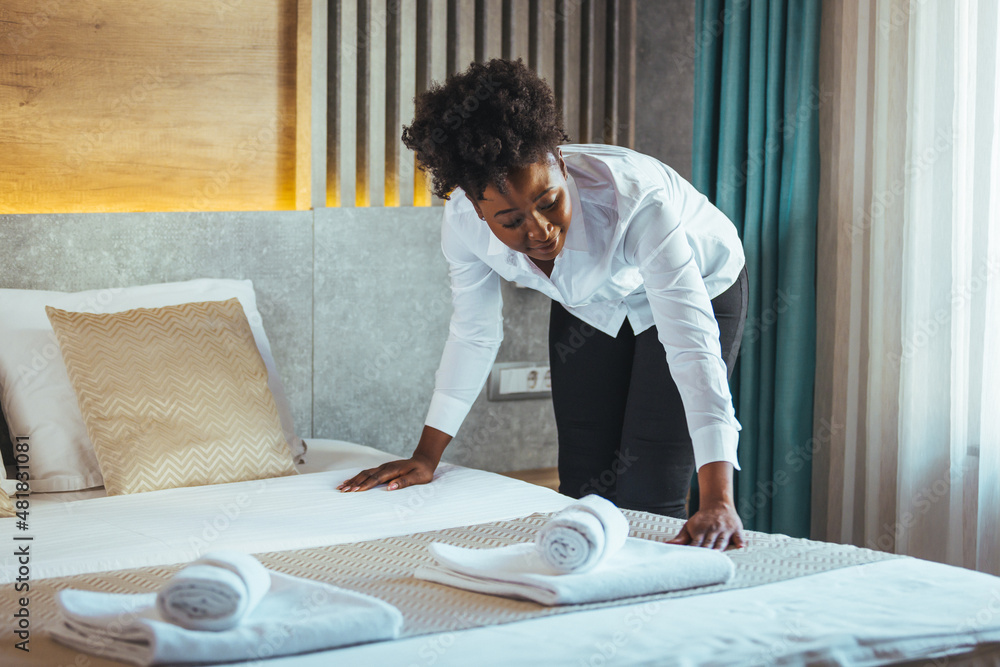 Housekeeper cleaning a hotel room. African housekeeper in a hotel room ...