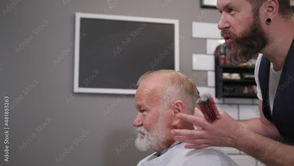 charming elderly man in barbers chair does a haircut and styling at a ...