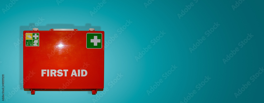 Banner with orange first aid case labeled in English First Aid hanging ...