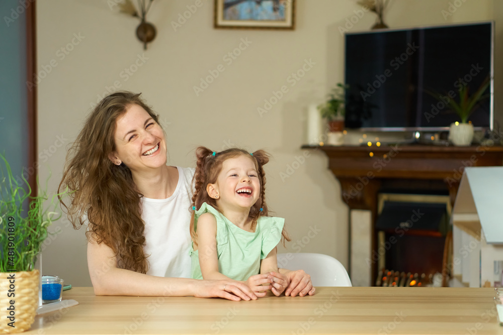 Portrait happy smile family. Mom and daughter at table look at cameras. two sisters laugh At ...