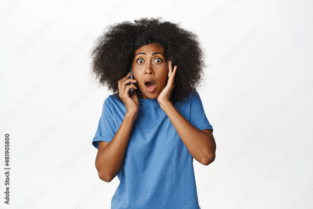 Shocked woman answer phone call, looks scared and worried, standing in ...