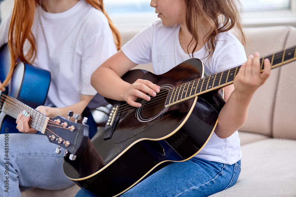Close-up photo of kid girl hands playing acoustic guitar, sitting with ...