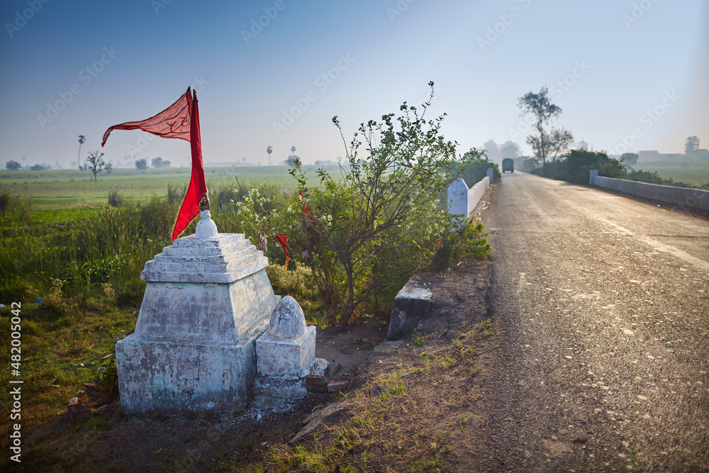 A small Indian temple/shrine with flag at the roadside. Only in the ...