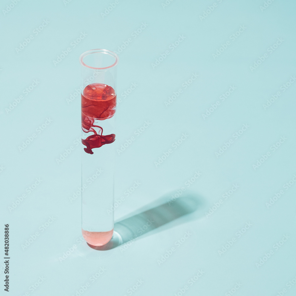 Blood dissolving in a transparent liquid in the test tube on a pastel ...