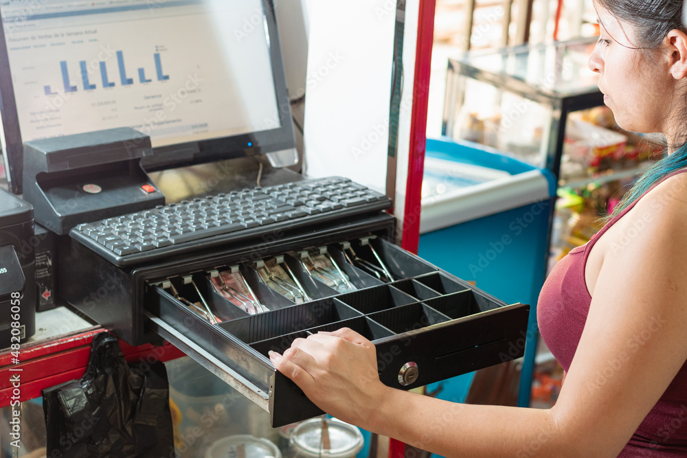 latina woman looking disappointed at the cash register of her business ...